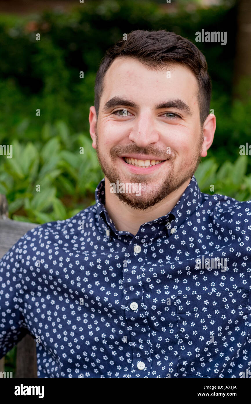 College grad student on a park bench on a beautiful university campus ...