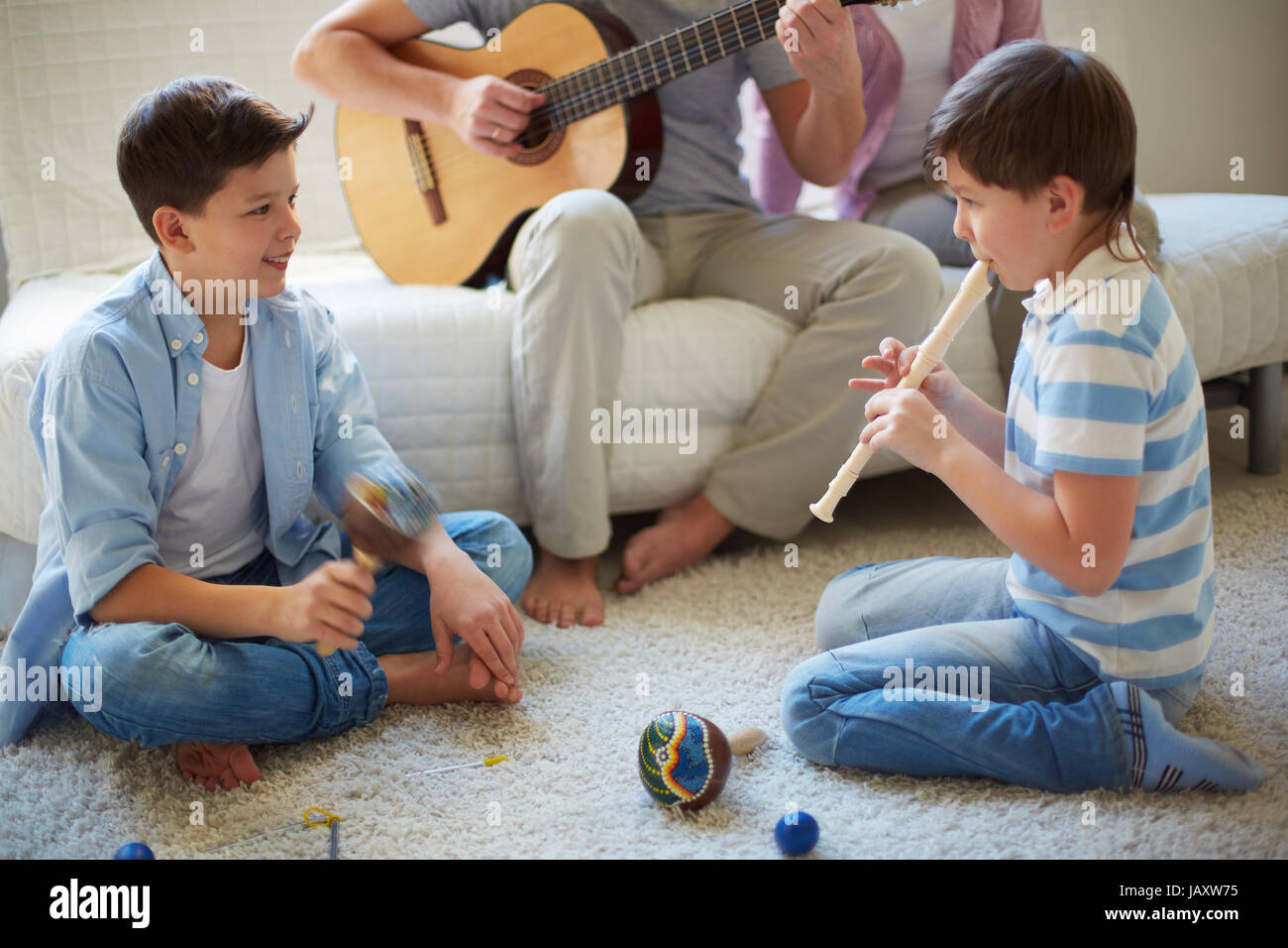 Portrait of handsome siblings playing musical instruments with their ...