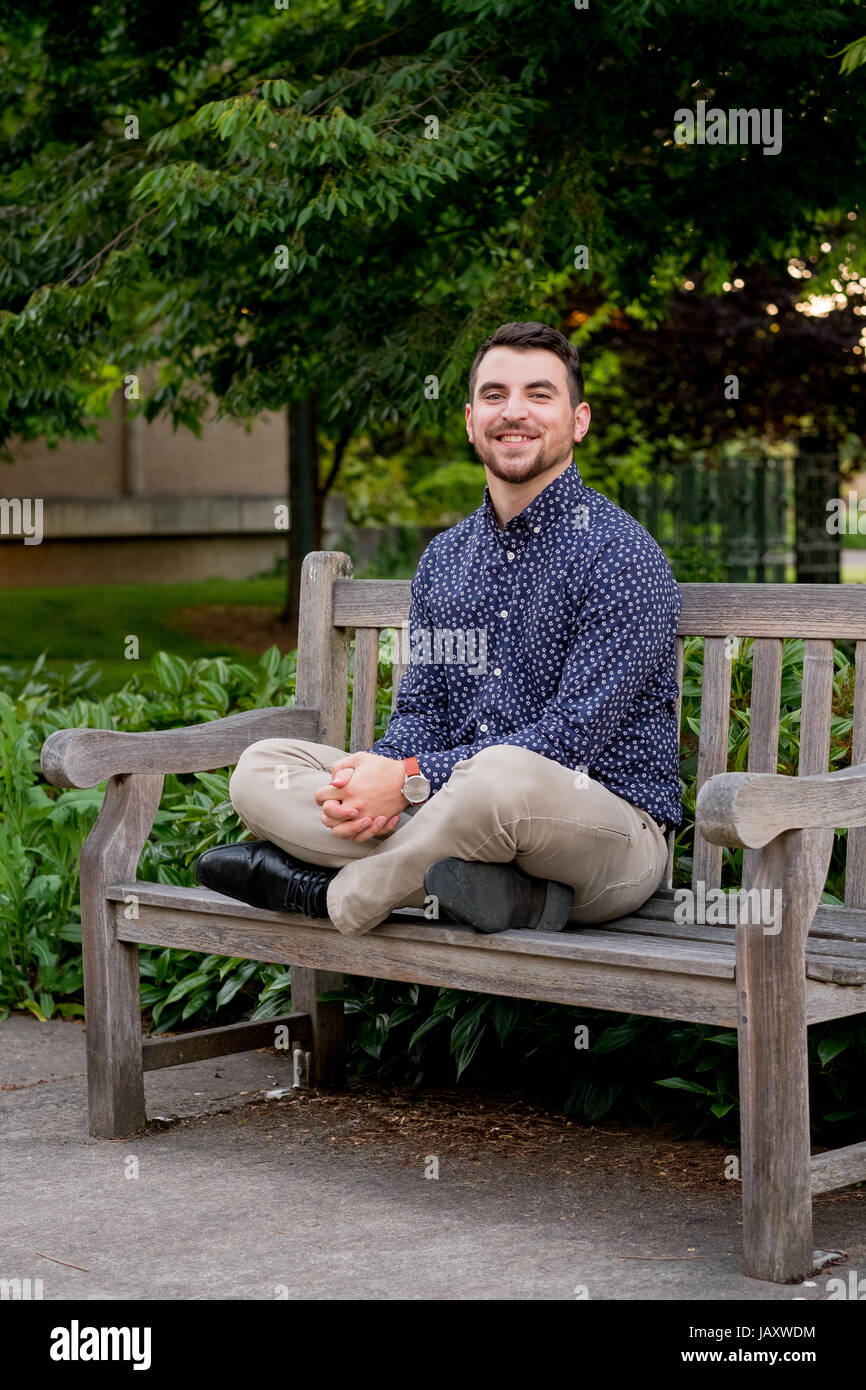 College grad student on a park bench on a beautiful university campus ...