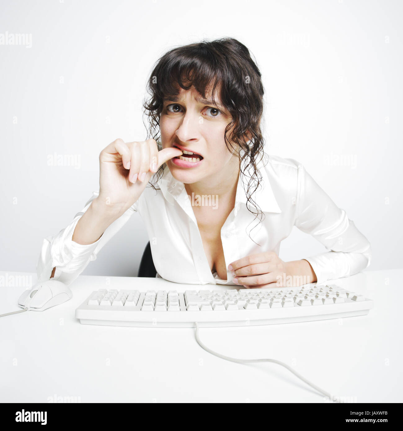 frontal portrait of a doubtful woman nail biting at her office desk ...