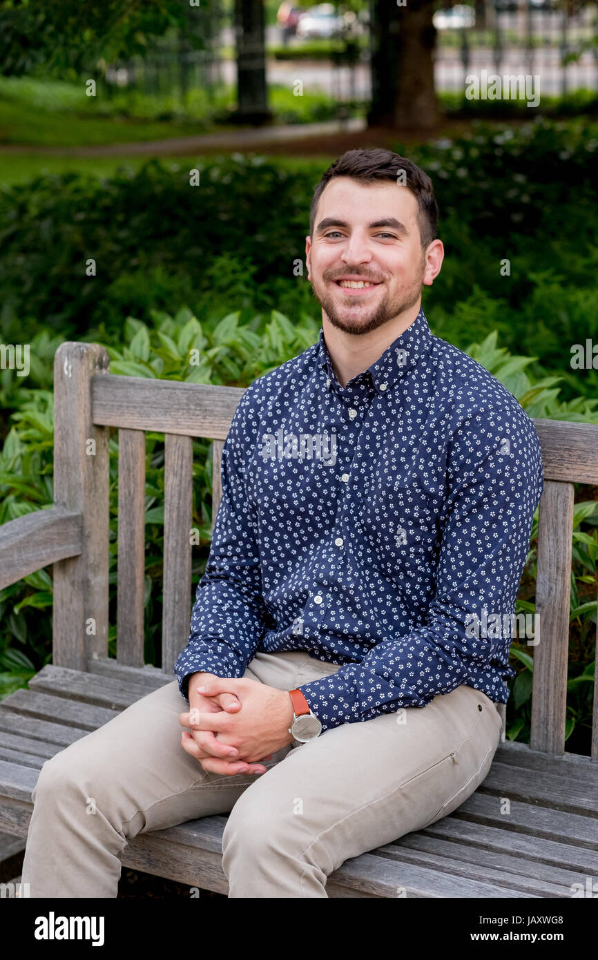 College grad student on a park bench on a beautiful university campus ...