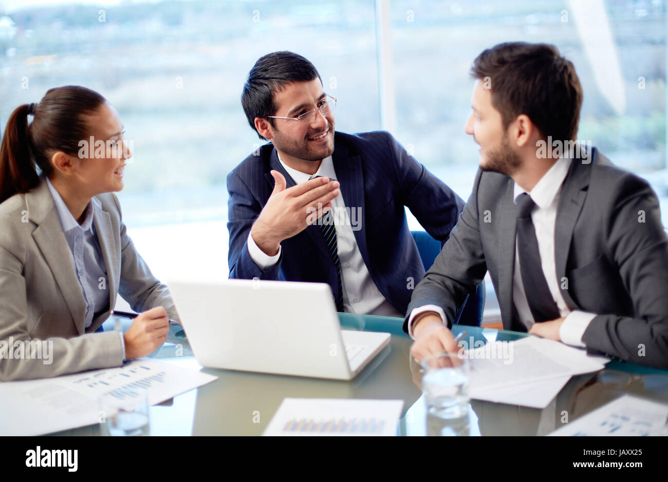 Portrait of three co-workers discussing business plan in office Stock ...