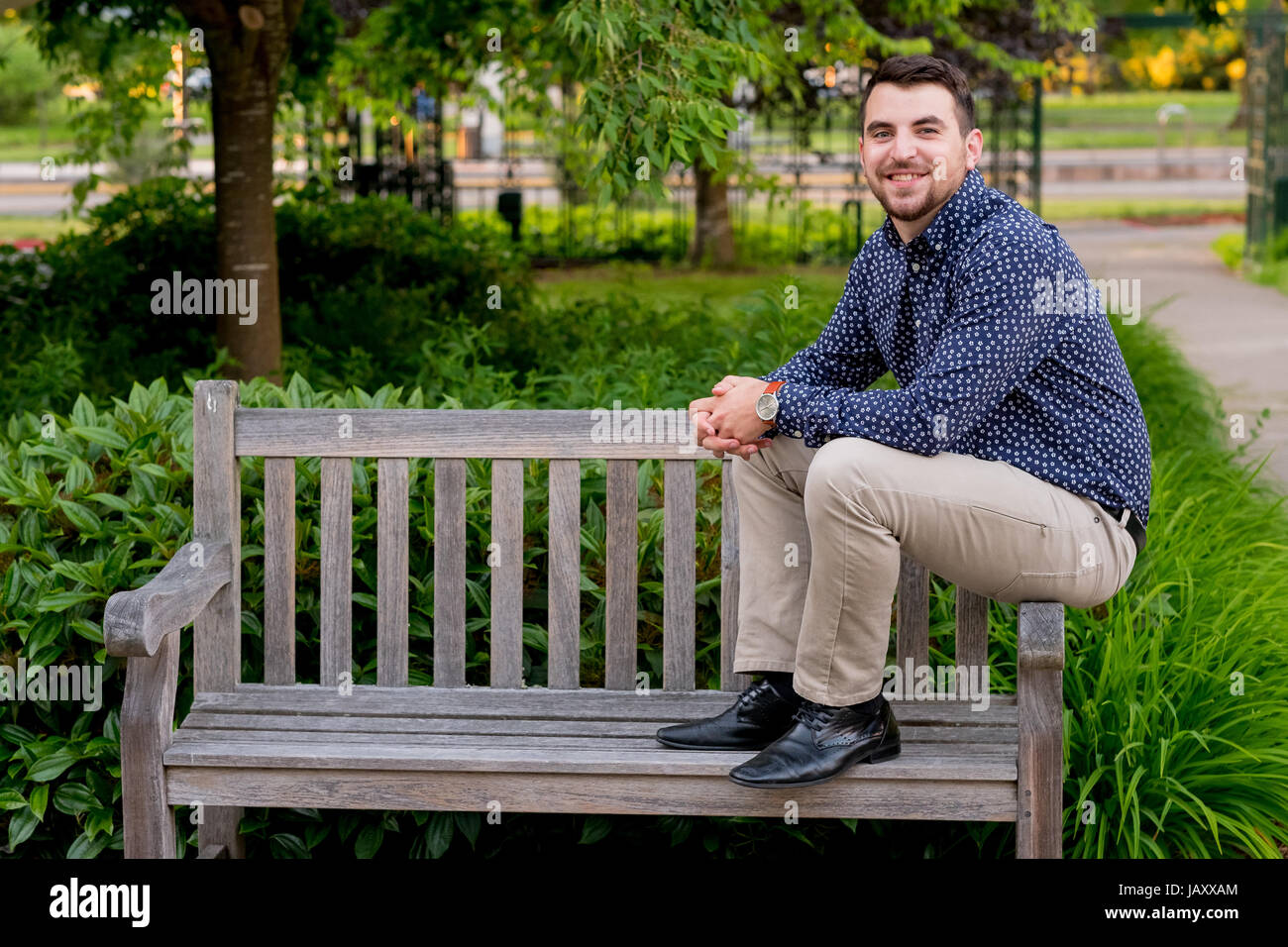 College grad student on a park bench on a beautiful university campus ...