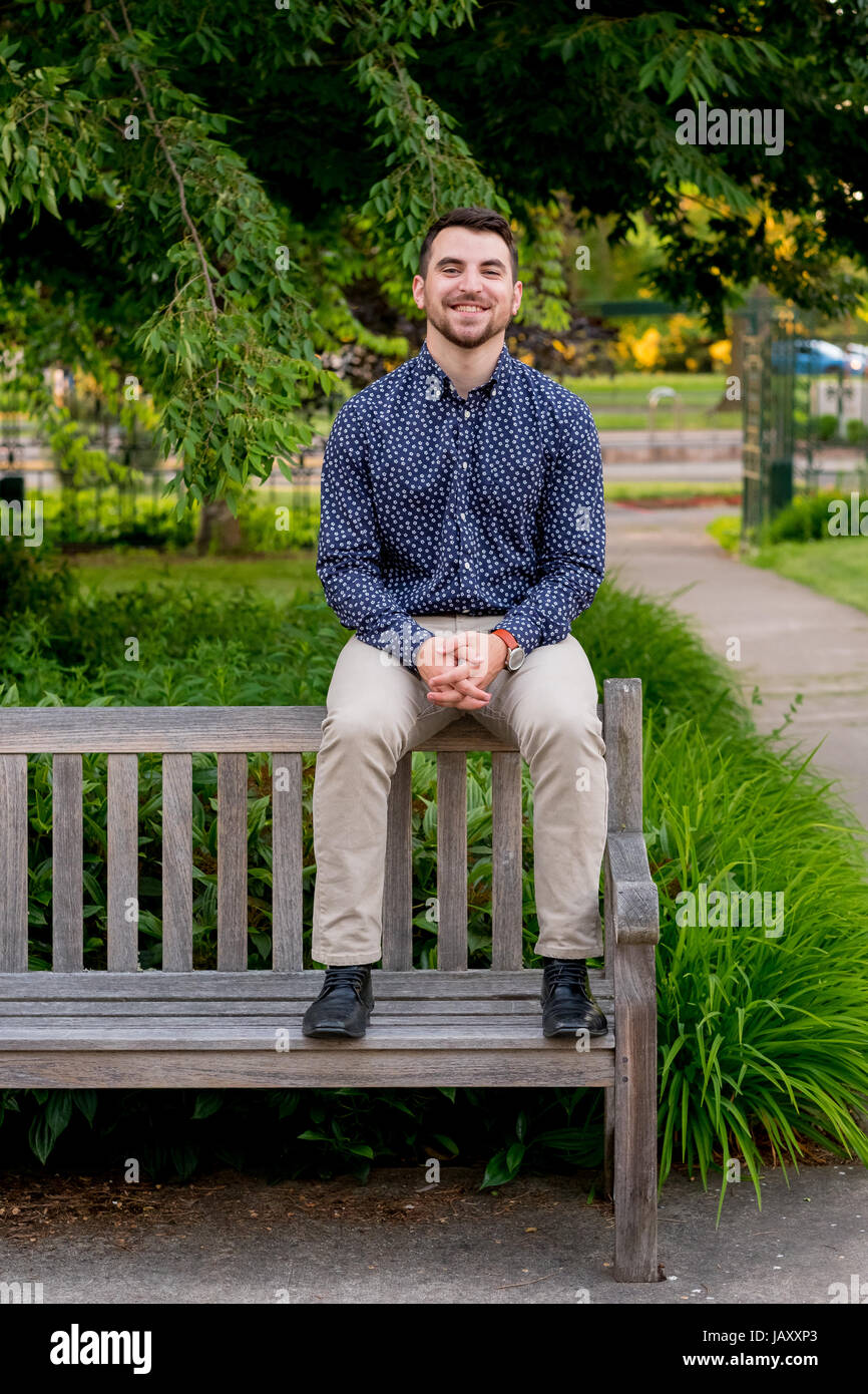 College grad student on a park bench on a beautiful university campus ...