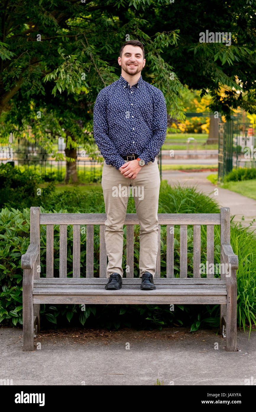 College grad student on a park bench on a beautiful university campus ...