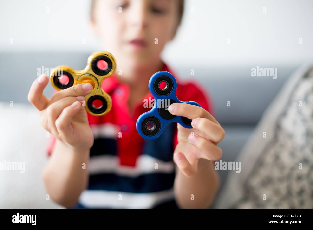 Little child, boy, playing with two fidget spinner toys to relieve ...