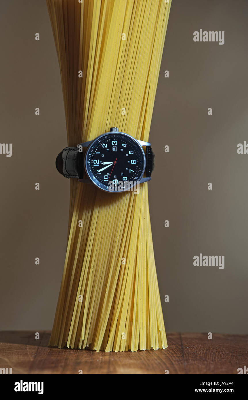 The image shows a still life with spaghetti and a wrist watch on a ...