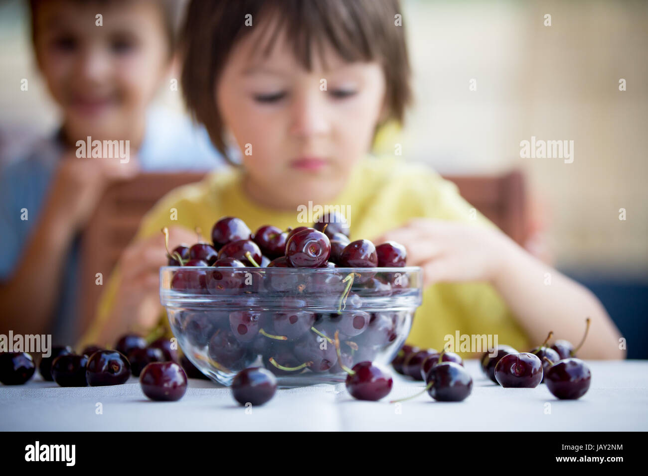 Cute little boy, eating sweet cherry outdoors, sitting on table Stock ...