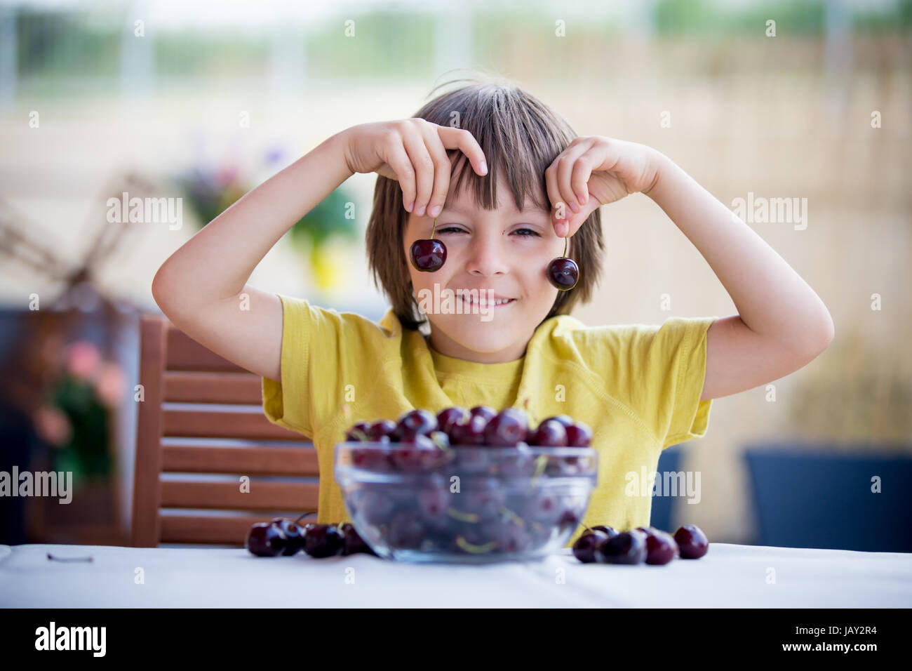 Cute little boy, eating sweet cherry outdoors, sitting on table Stock ...