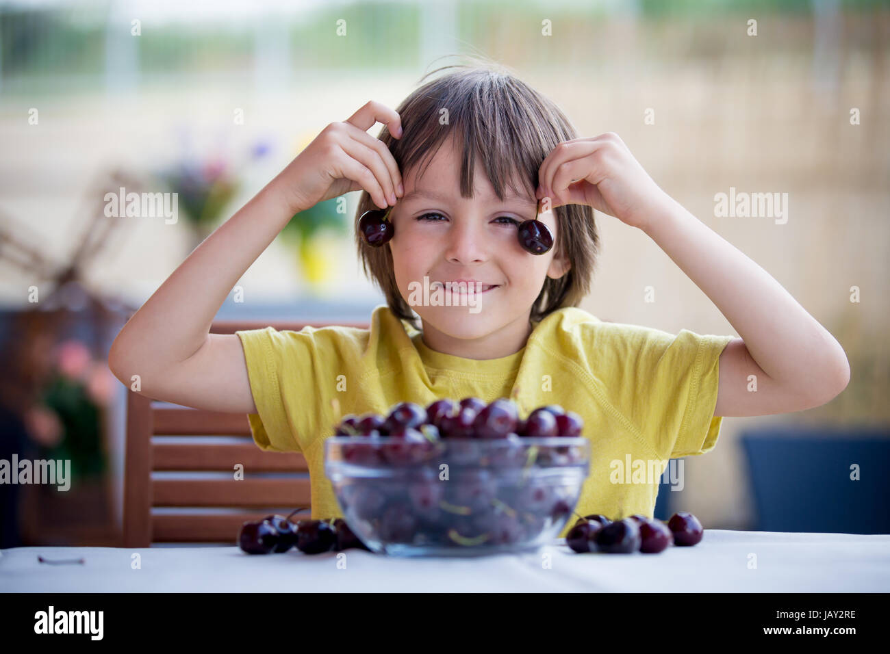 Cute little boy, eating sweet cherry outdoors, sitting on table Stock ...