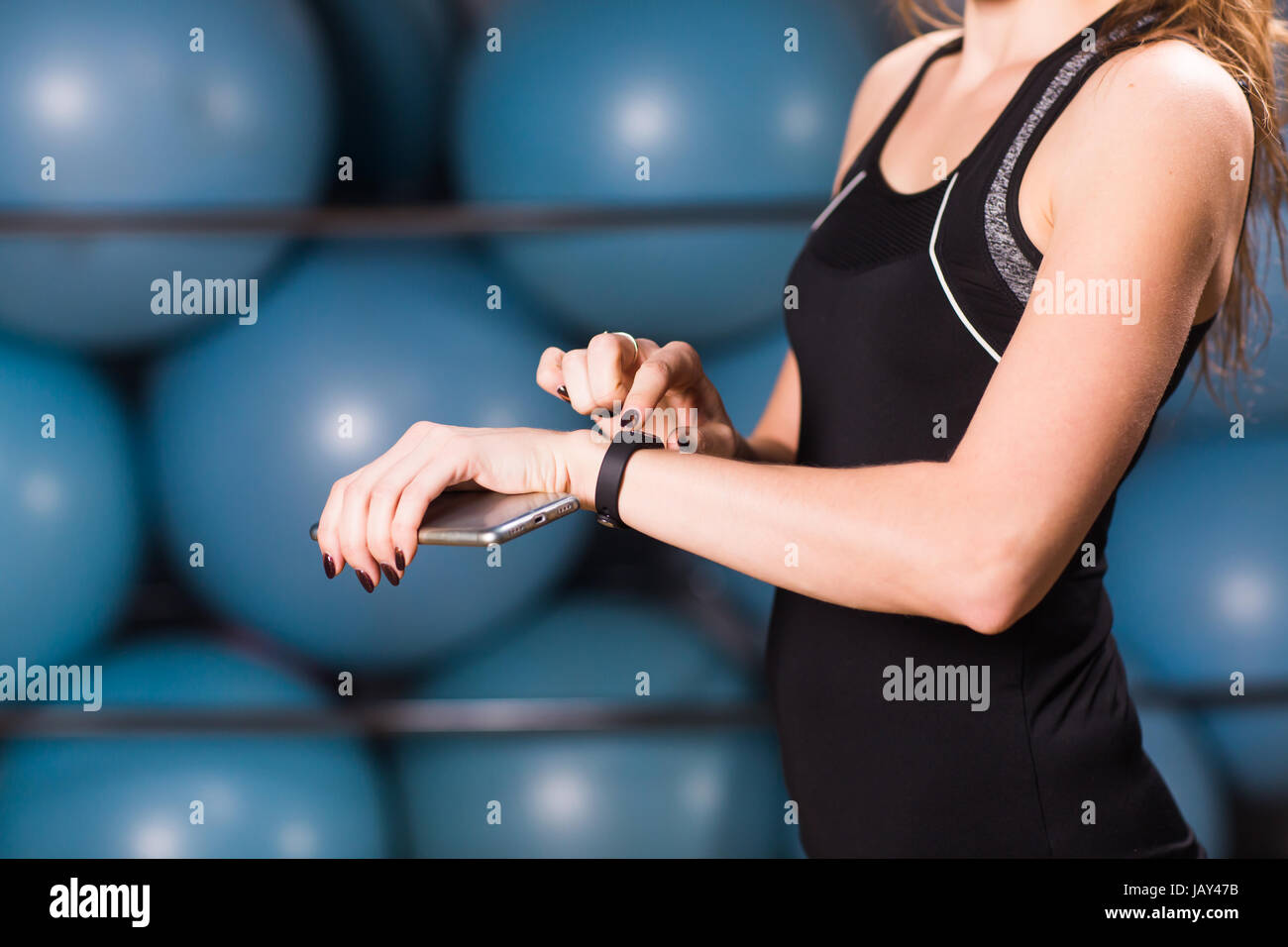 Close-up of female hands with fitness tracker and smartphone in gym ...
