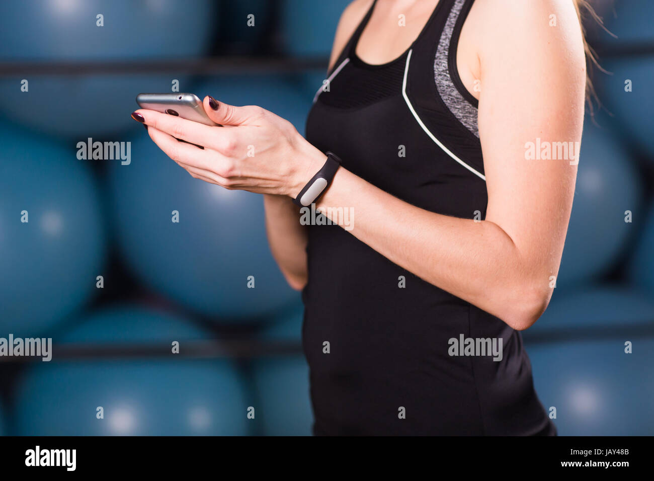 Close-up of female hands with fitness tracker and smartphone in gym ...