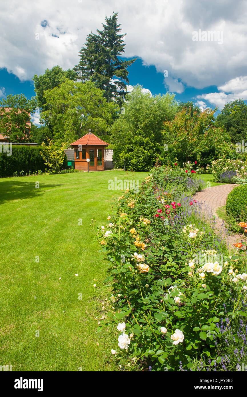 Beautiful garden with blooming roses and a small gazebo Stock Photo - Alamy