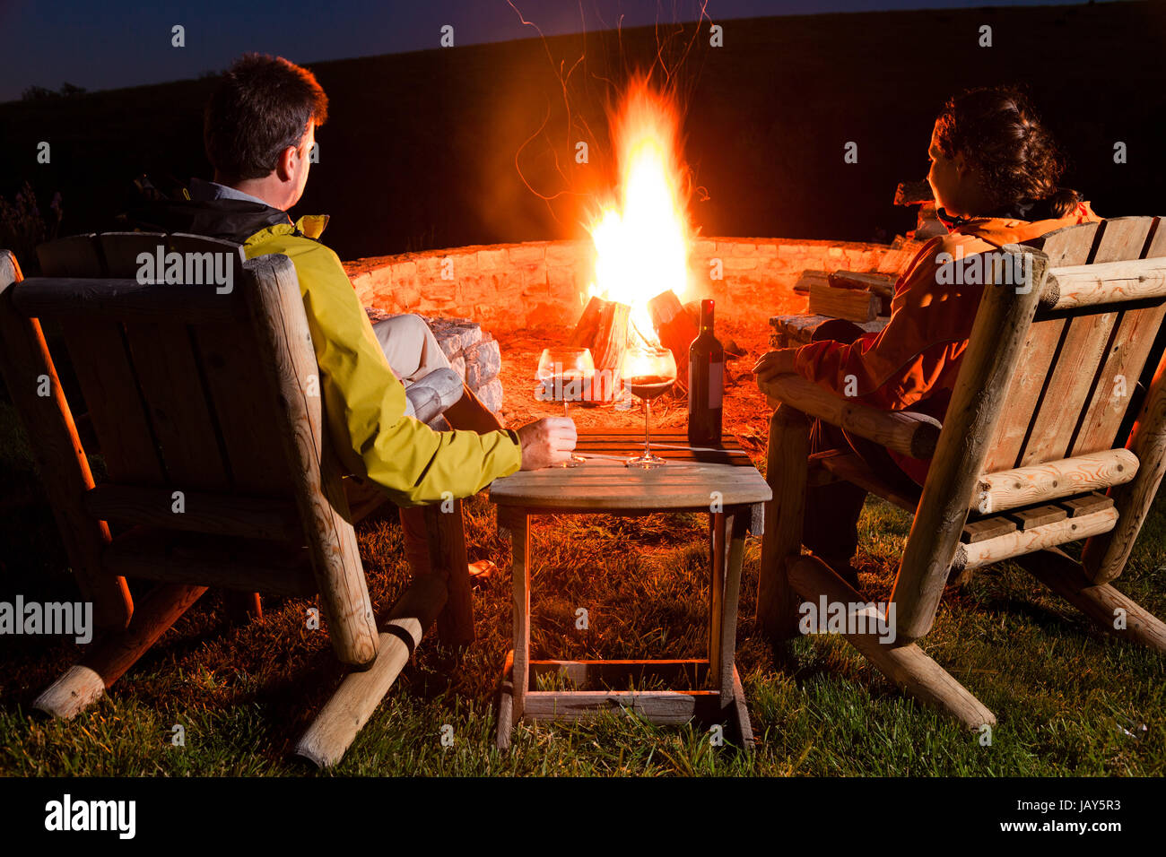 A couple is sitting by the bonfire, enjoying wine Stock Photo - Alamy