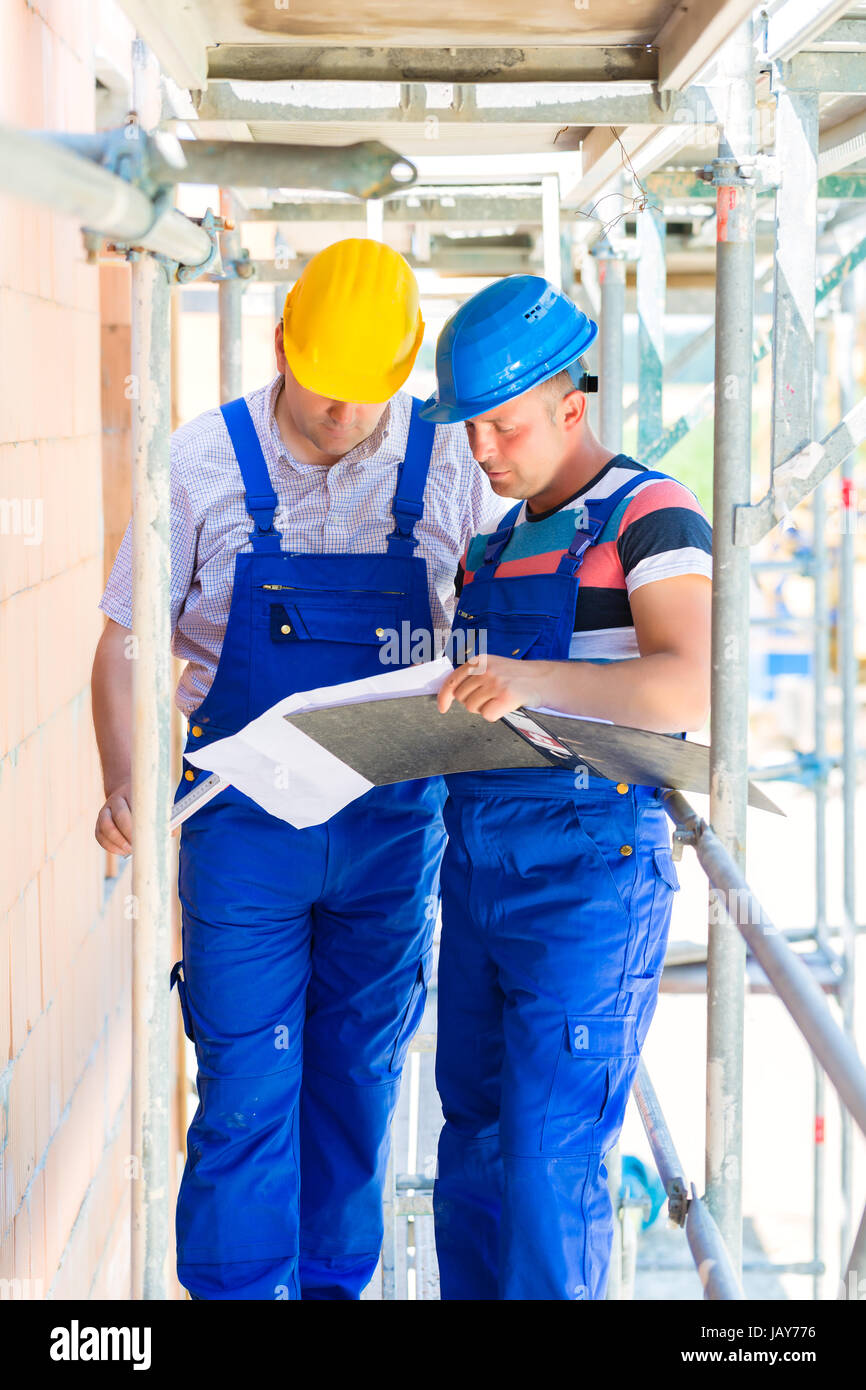 Construction Team with building plans on site Stock Photo - Alamy