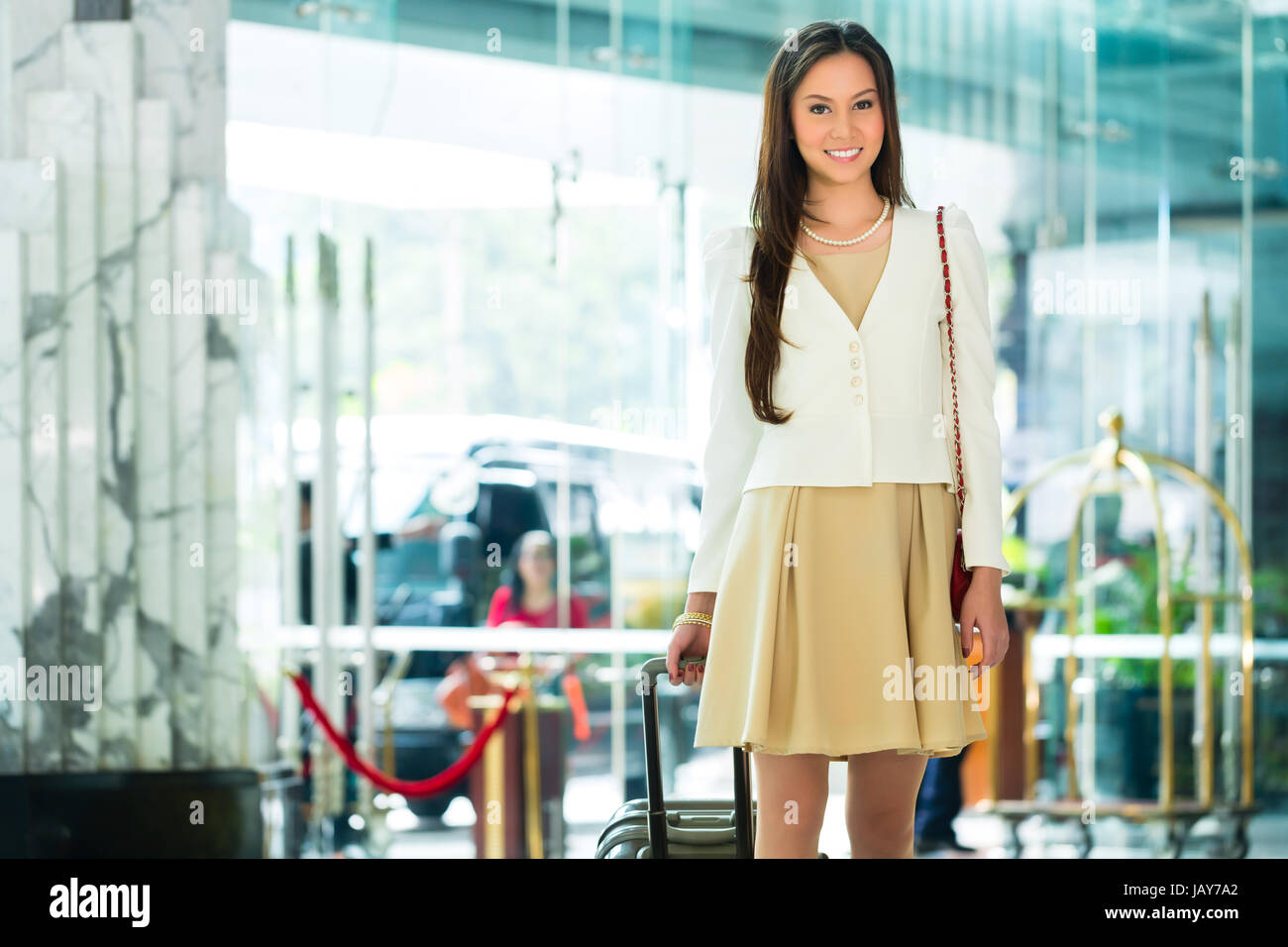 Asian Chinese woman arriving at luxury hotel in business clothes with ...