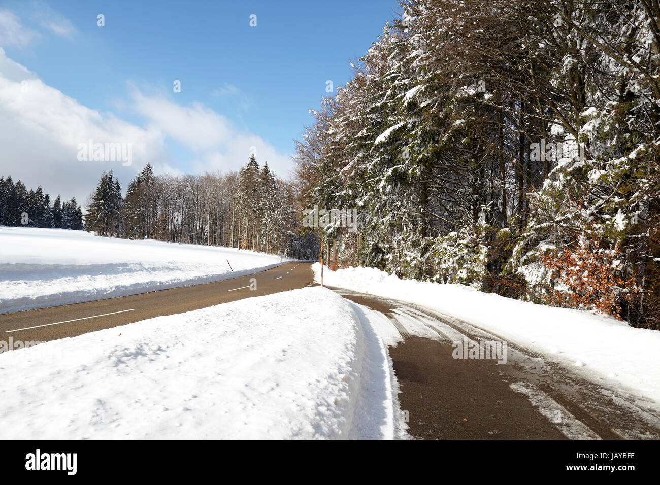 A winter landscape with a street taken at daylight with a blue sky and ...