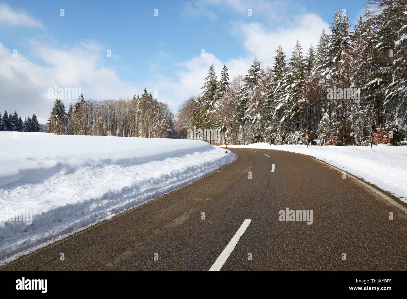 A winter landscape with a street taken at daylight with a blue sky and ...