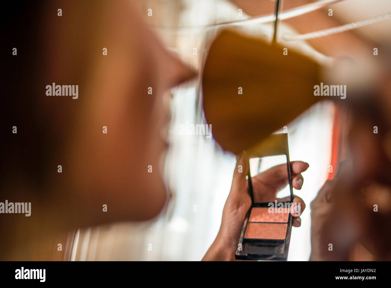 A woman doing makeup using blusher Stock Photo - Alamy