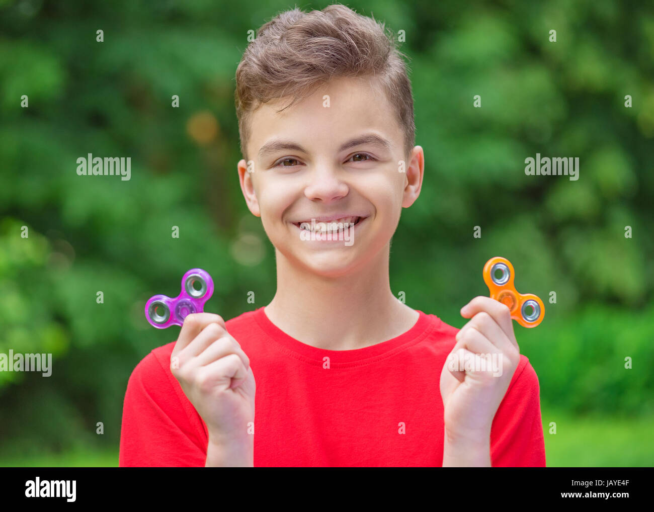 Young teen boy holding popular fidget spinner toy - outdoors portrait ...