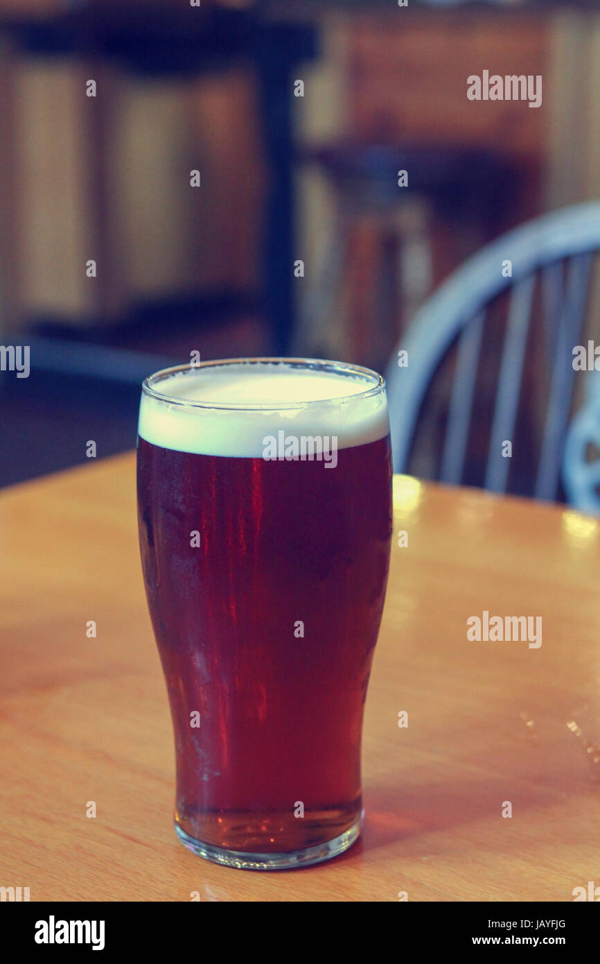 Big glass of dark ale on a table in a pub Stock Photo - Alamy