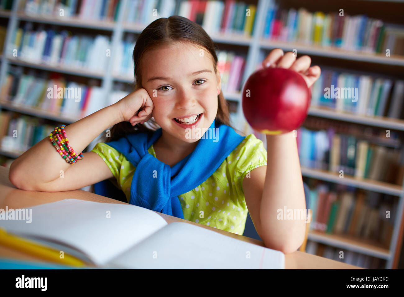 Portrait of happy schoolgirl with big red apple looking at camera in ...