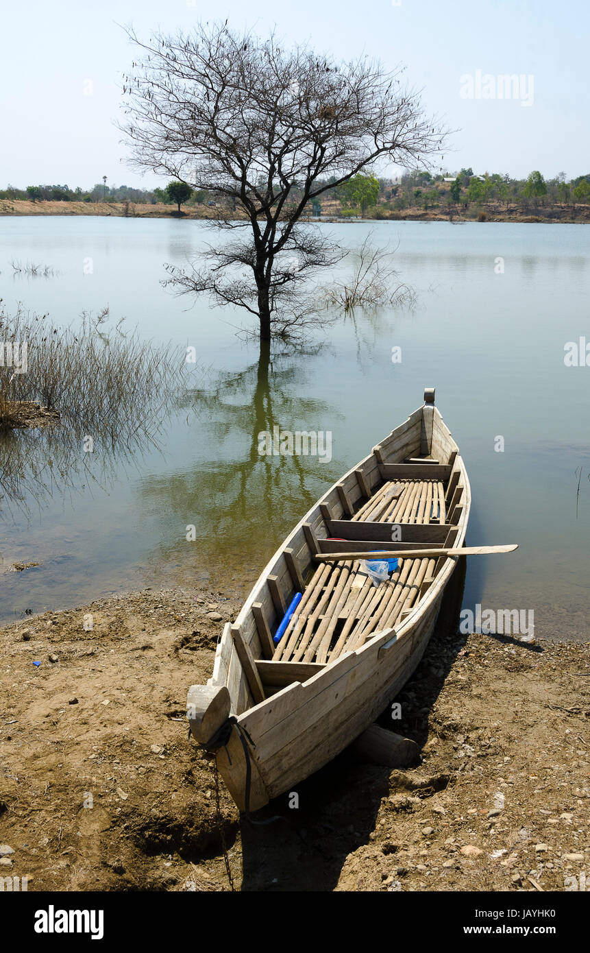 Wooden boat on lake shore, tree in lake, near Myaing, Myanmar Stock ...