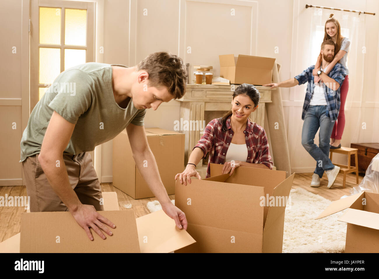 Young man and woman opening cardboard boxes in new house Stock Photo ...
