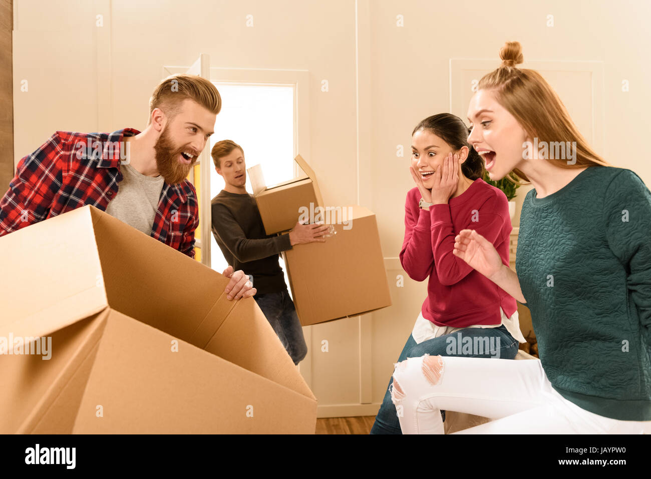 cheerful friends holding cardboard boxes at new home Stock Photo - Alamy