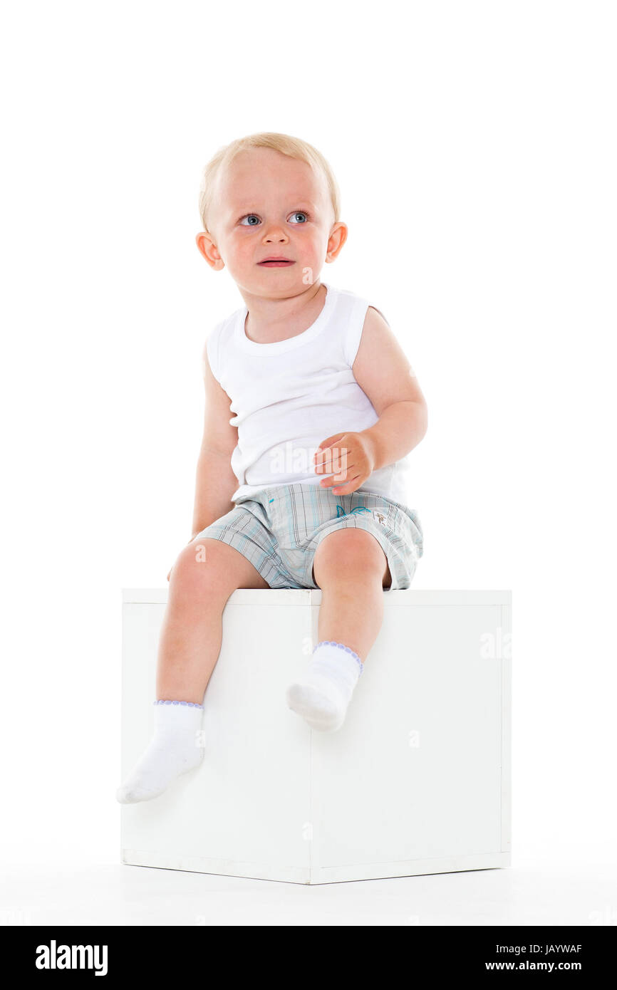 Unhappy yearling baby boy sits on cube on a white background Stock ...