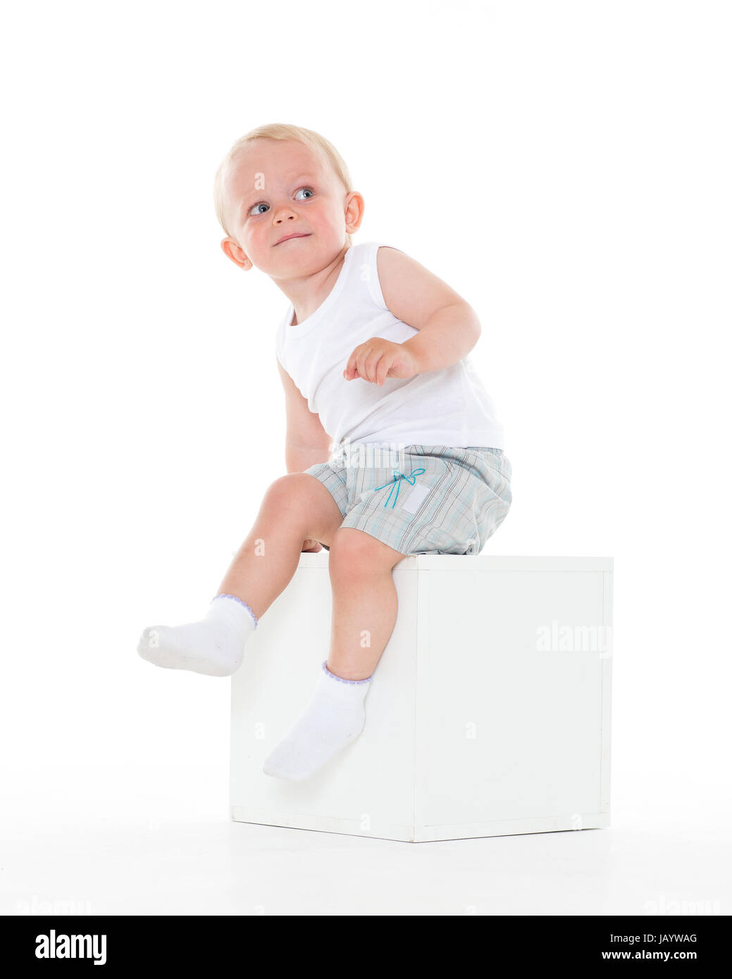 Unhappy yearling baby boy sits on cube on a white background Stock ...