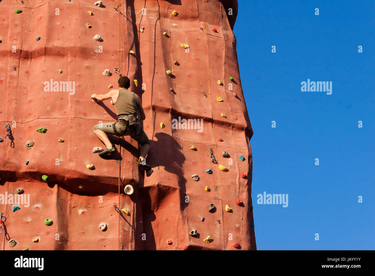 A young man climbing an artificial rock wall outdoors Stock Photo - Alamy