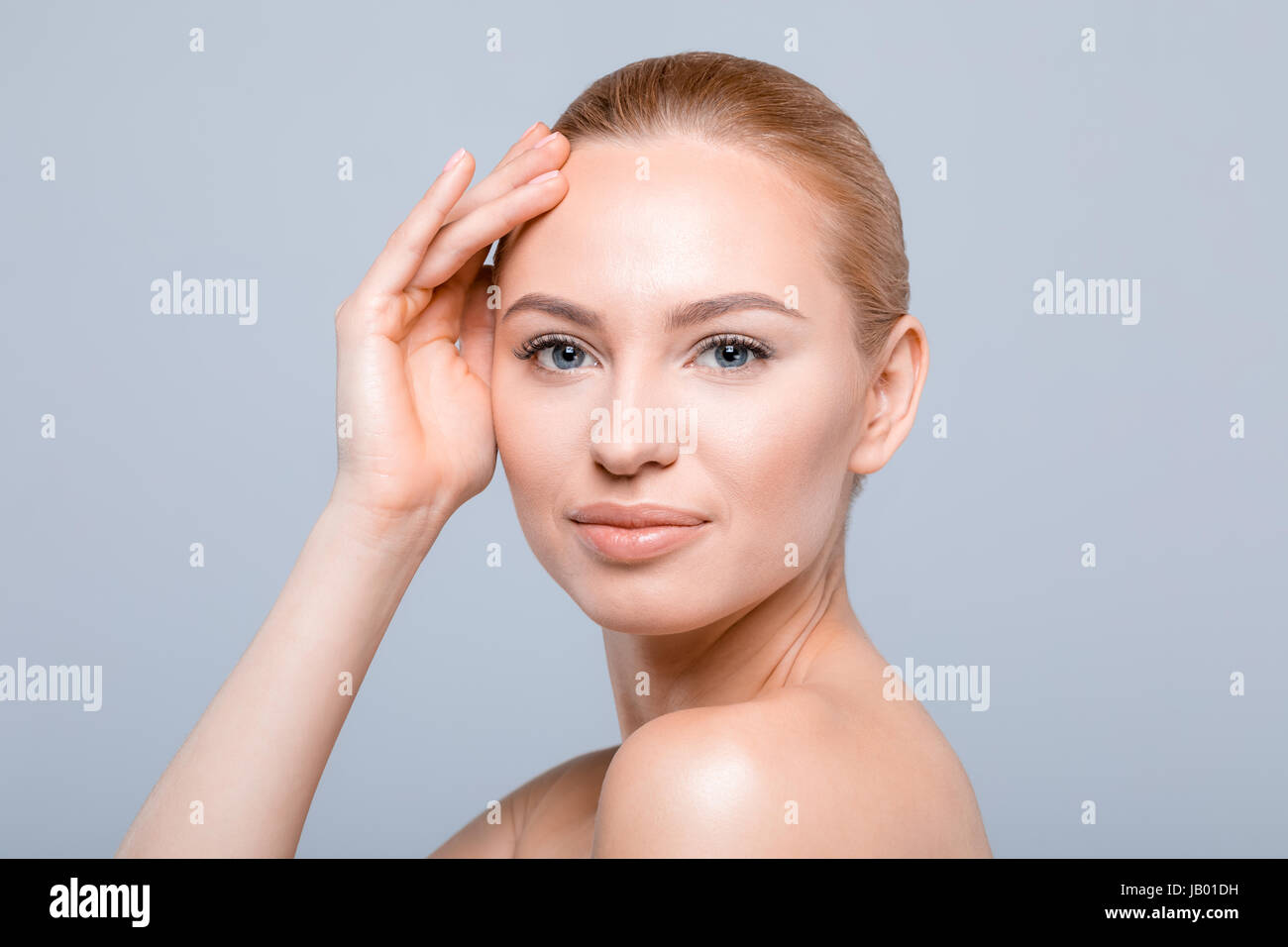 Close-up portrait of gorgeous young woman with hand on forehead looking ...