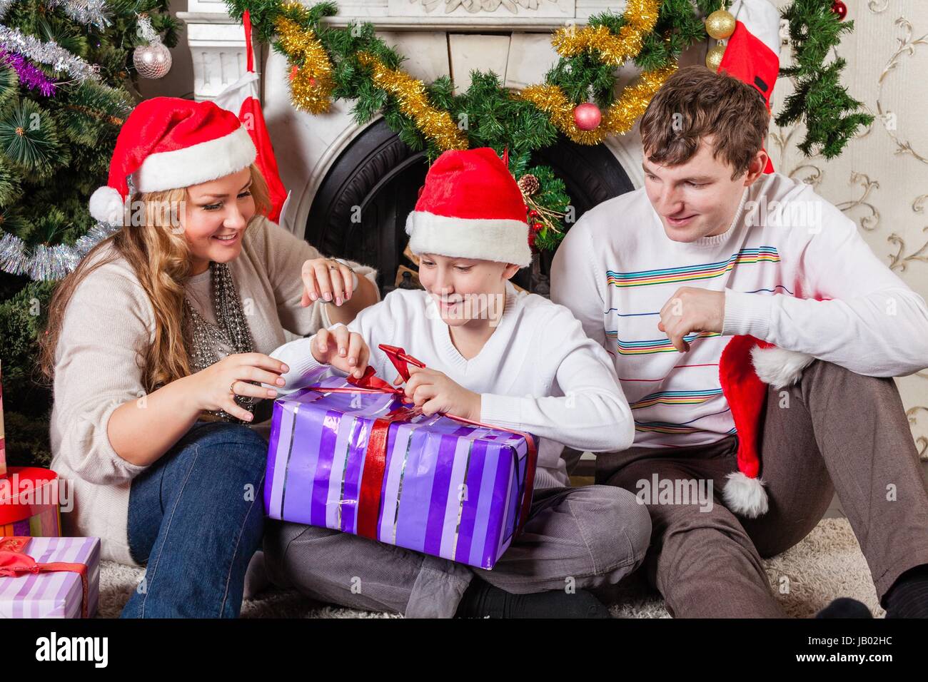 Happy family with gifts sitting near Christmas tree at home Stock Photo ...
