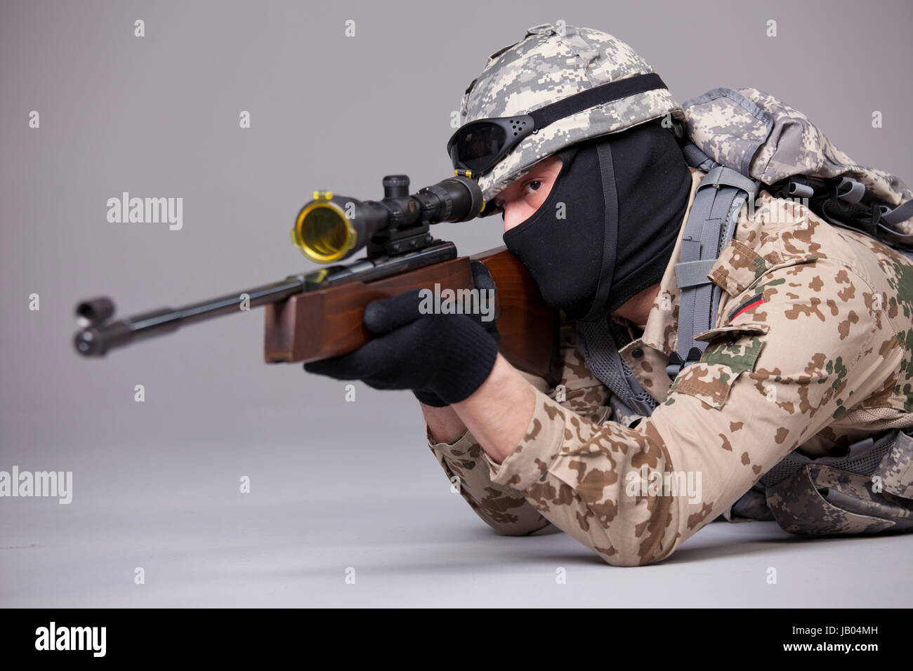 Sniper aiming - military scene shot in a studio over grey background ...