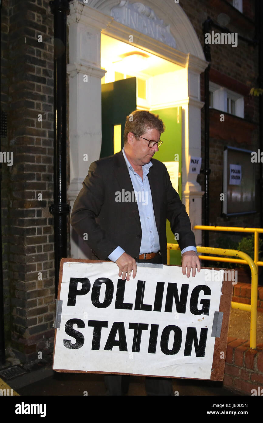 A poll clerk removes the polling station sign as voting closes at 10pm ...
