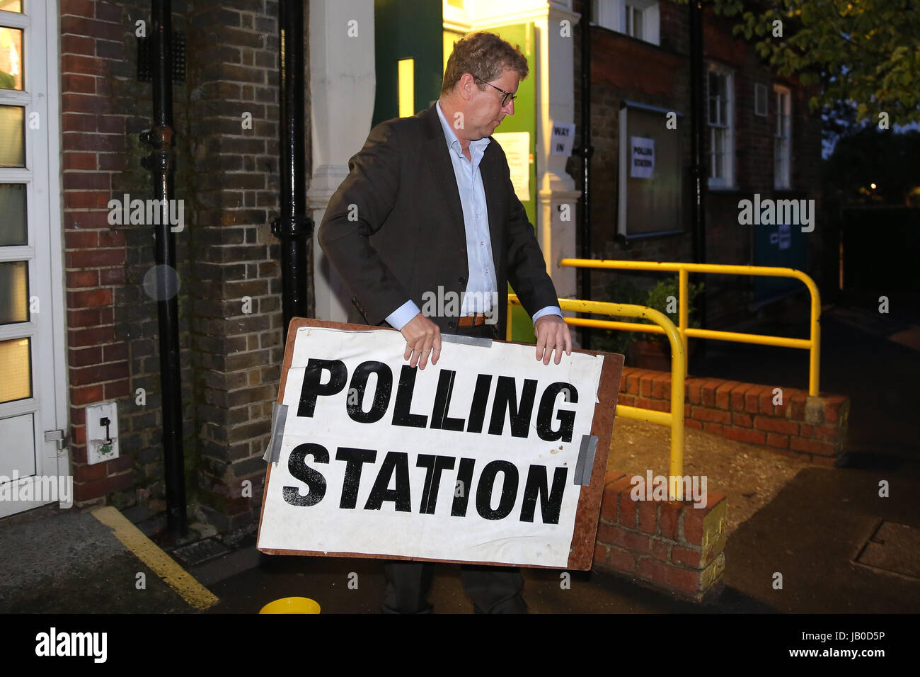 A poll clerk removes the polling station sign as voting closes at 10pm ...