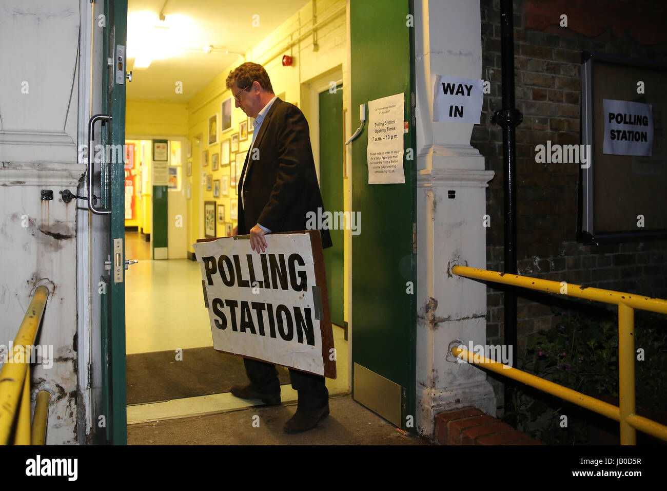 A poll clerk removes the polling station sign as voting closes at 10pm ...