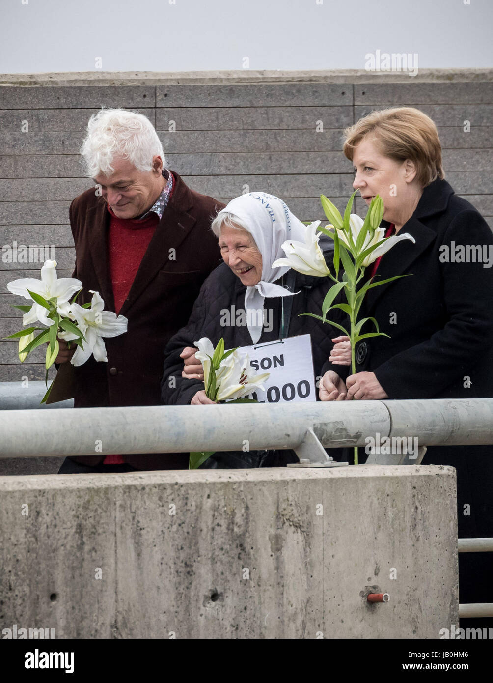 German Chancellor Angela Merkel (R) holds flowers in her hands as she ...