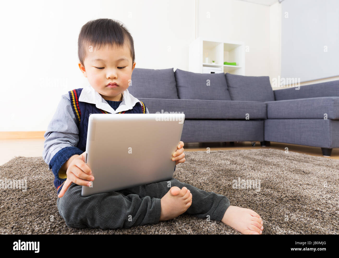 Asian little boy using tablet at home Stock Photo - Alamy