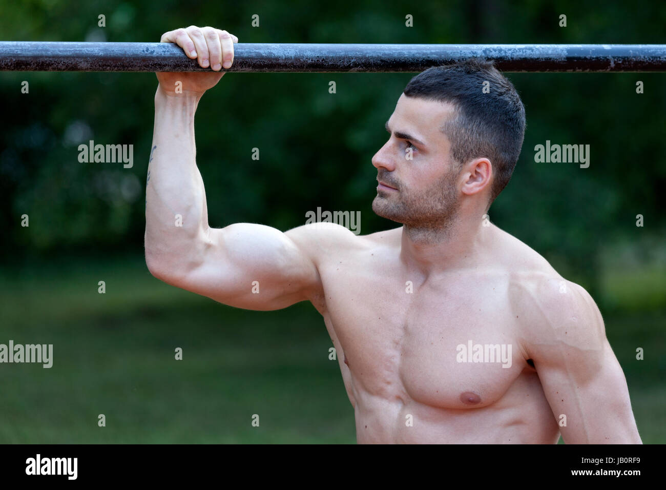 Young fit man doing exercises on the horizontal bar and shows his ...