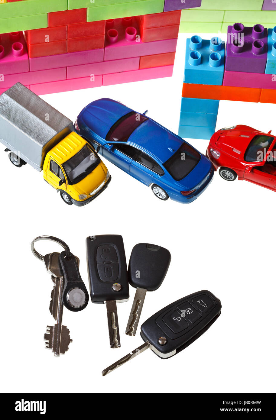 top view of door key, vehicle keys, three model cars and plastic block ...