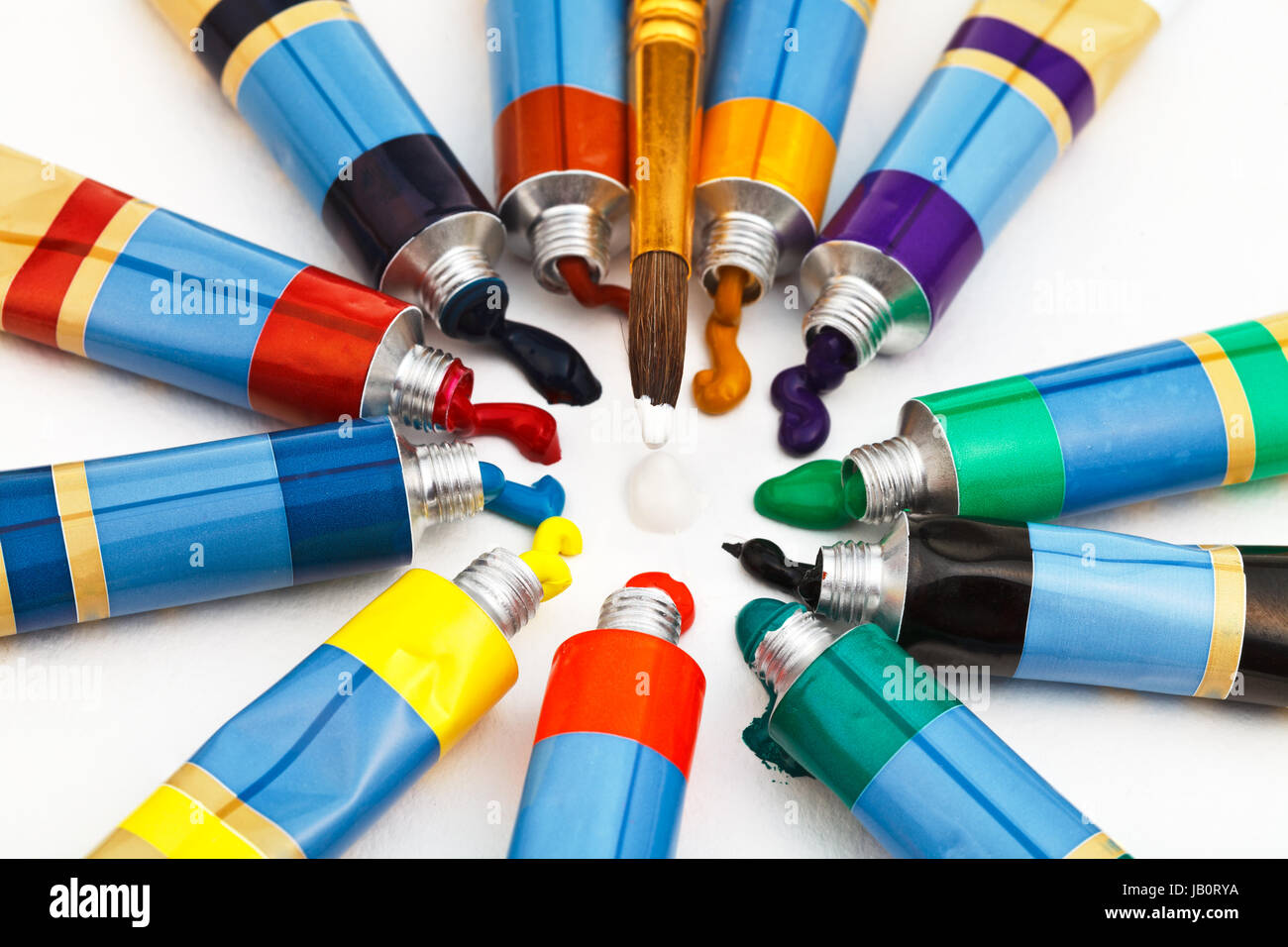 round paintbrush and set of multicolored tubes with squeezed ...