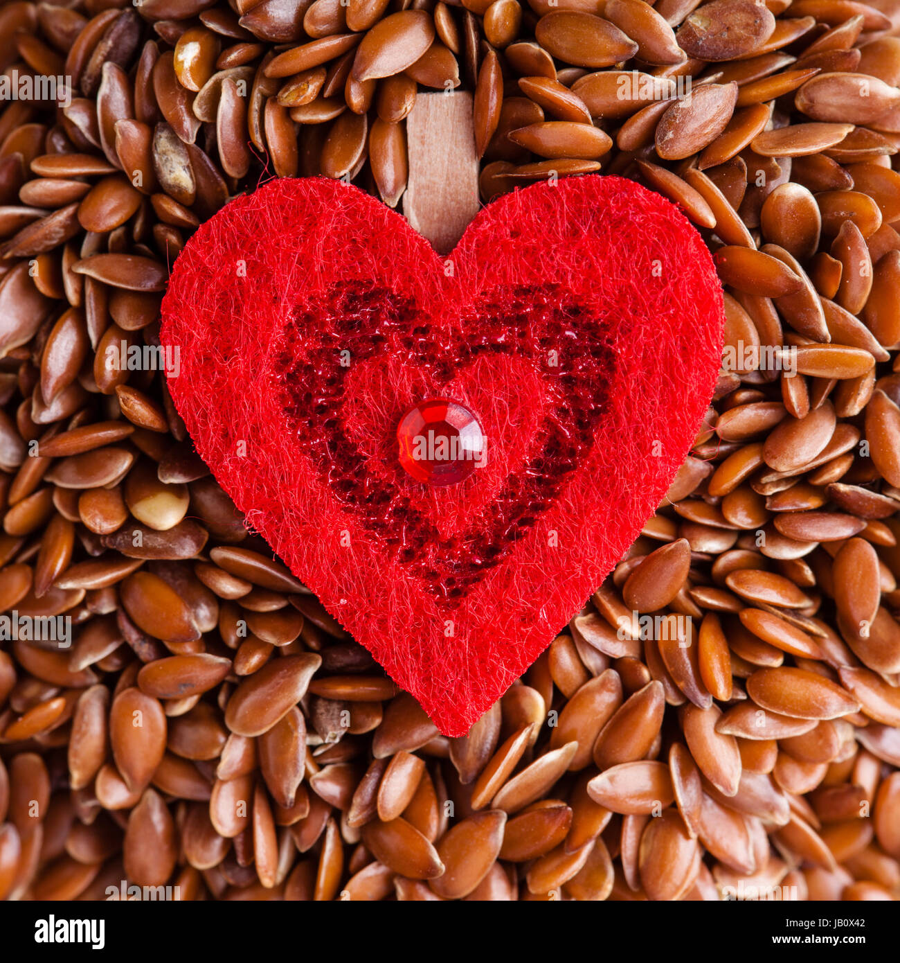 diet healthcare concept. Brown raw flax seeds linseed and red heart symbol. Healthy food for ...