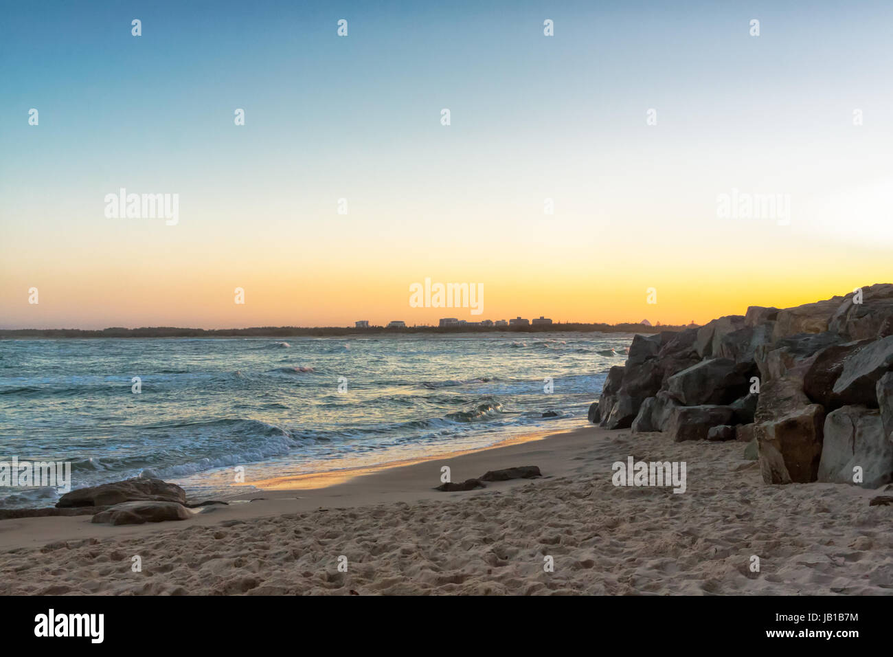 The setting sun colors the waves of the Pacific ocean beautifully at ...