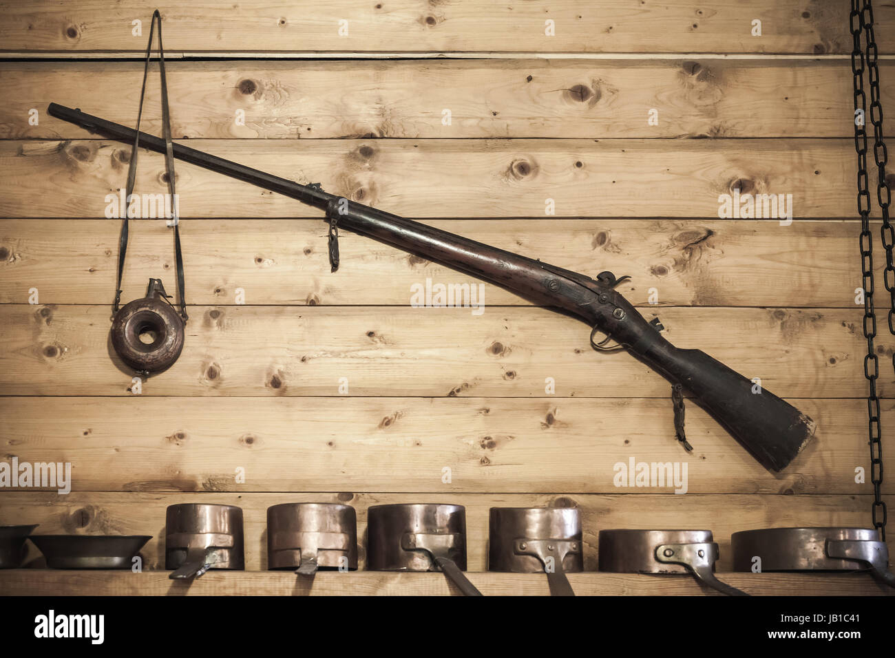 Old hunting rifle with powder flask hanging on wooden wall Stock Photo ...