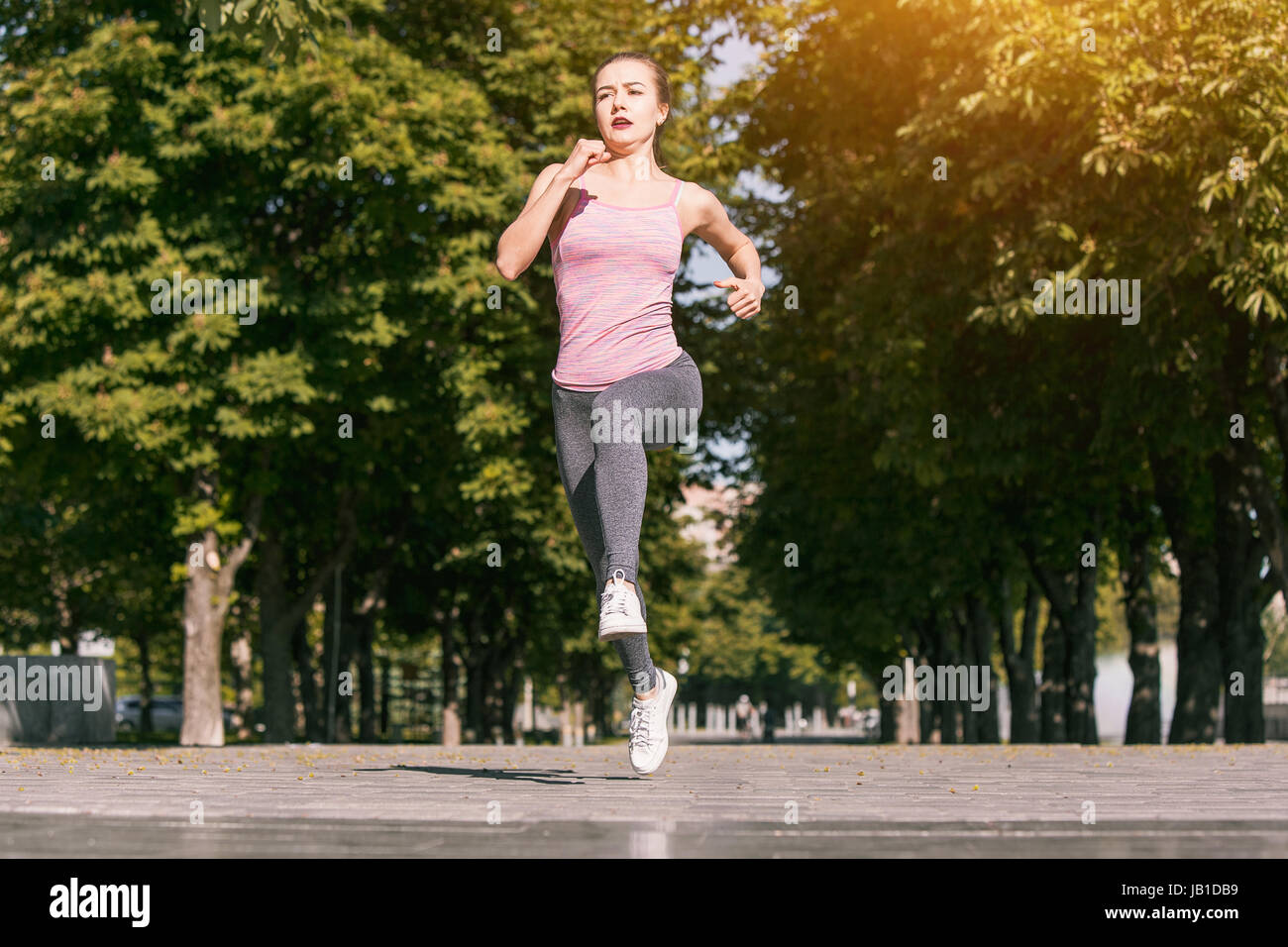 Pretty sporty woman jogging at park in sunrise light Stock Photo - Alamy