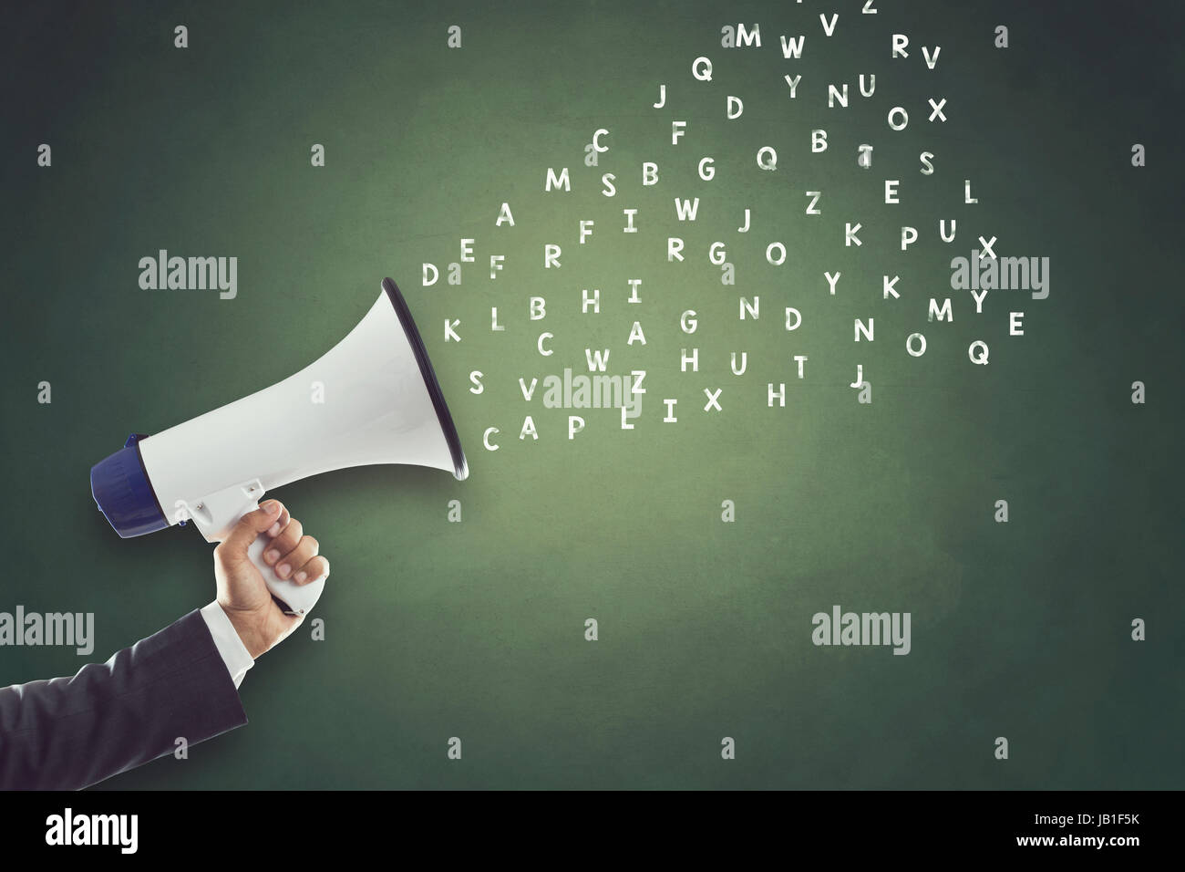 Businessman holding megaphone with flying alphabets on green chalkboard ...