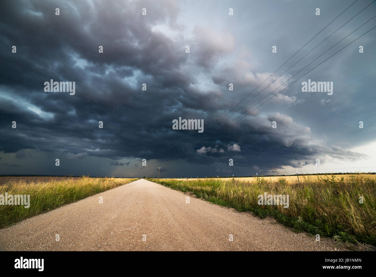 Empty dirt road through a field with dramatic clouds and stormy sky in ...