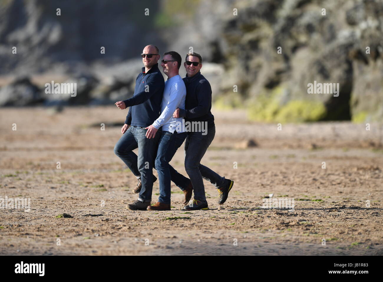 Three men walking and dancing in tandem on the beach Stock Photo - Alamy
